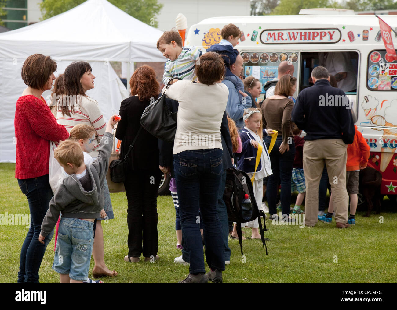 Children and families queue for ice cream from an ice cream van ...