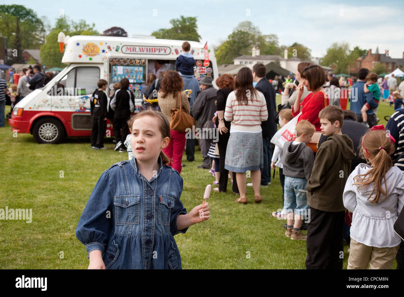 Children and families queue for ice cream from an ice cream van ...
