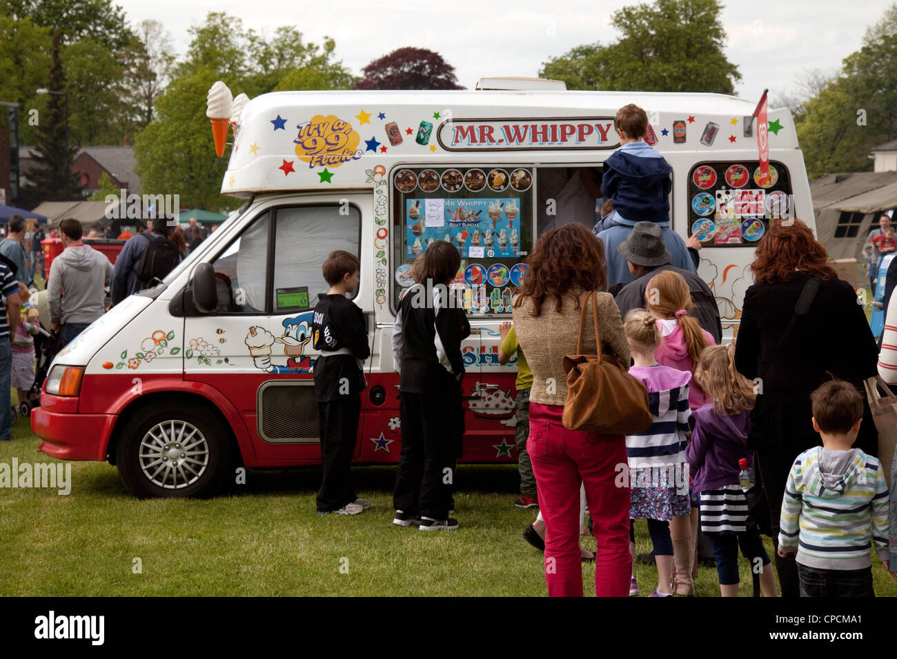 Children and families queue for ice cream from an ice cream van ...