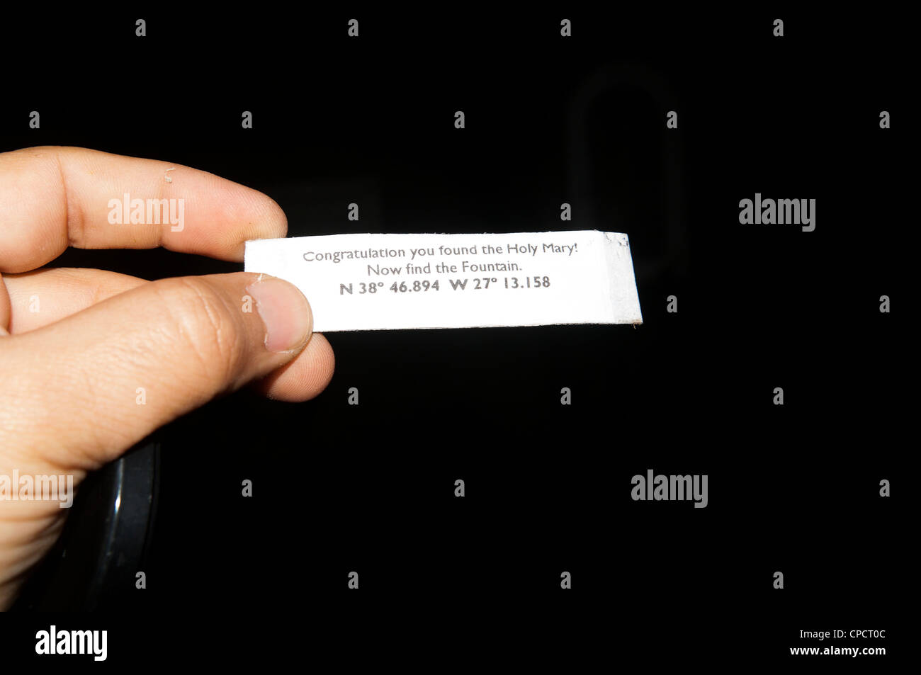 Geocaching clue with GPS coordinates held by hand during a multi-cache ...