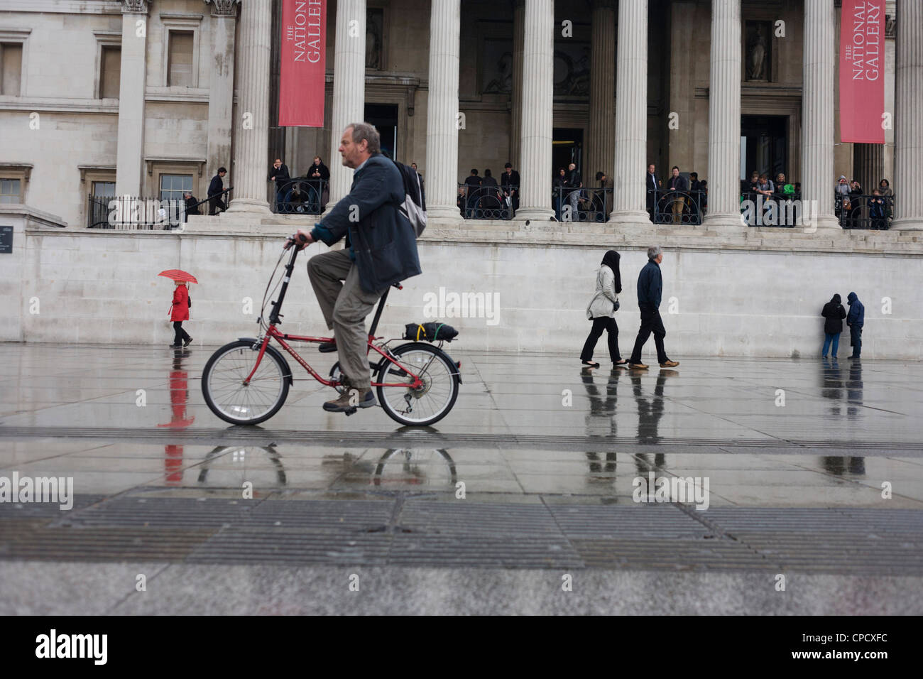 People and cyclist pass-by on the pedestrian pavement in Trafalgar ...
