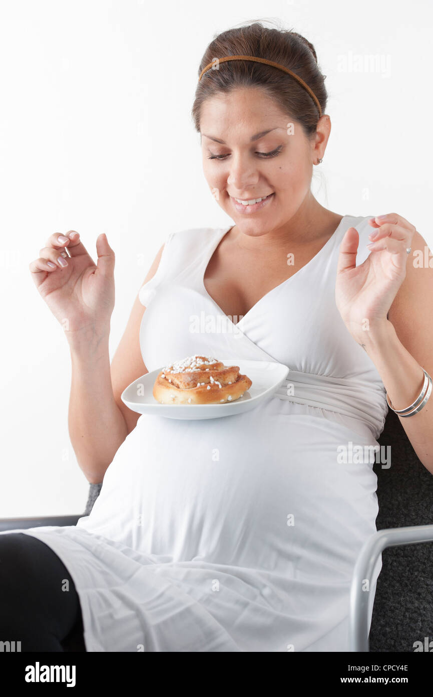 Pregnant woman balancing plate with a sweet bun on her stomach Stock ...