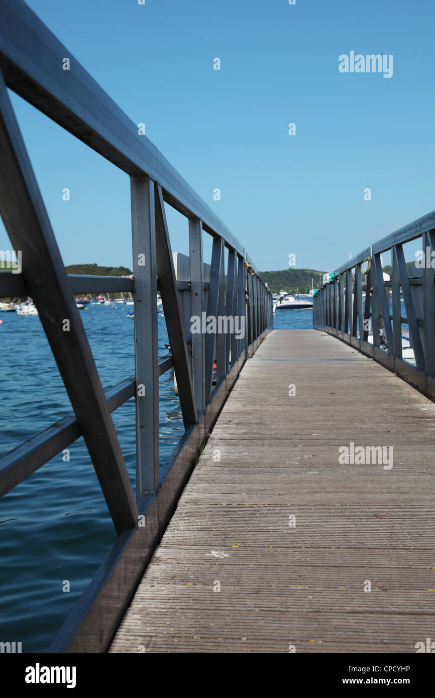 A seaside pier with metal railings and boats in the background Stock ...