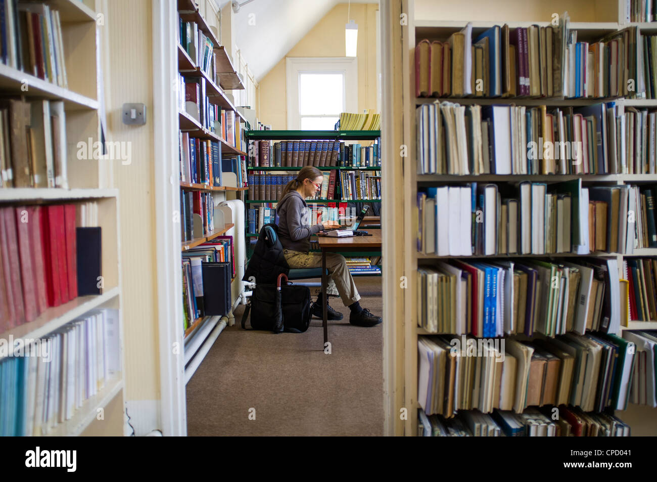 a woman working on her laptop computer in the reference section of the ...