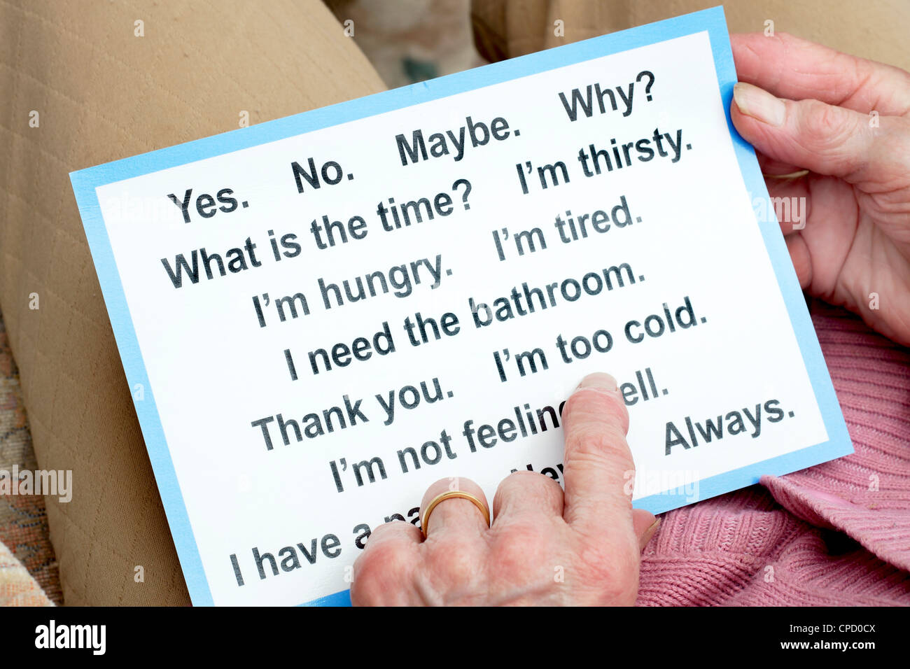 Elderly woman using a communication card pointing out she feels cold ...