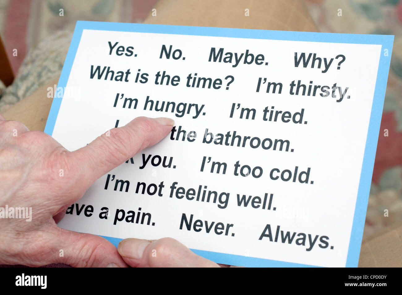 Elderly woman using a communication card pointing out she is hungry ...