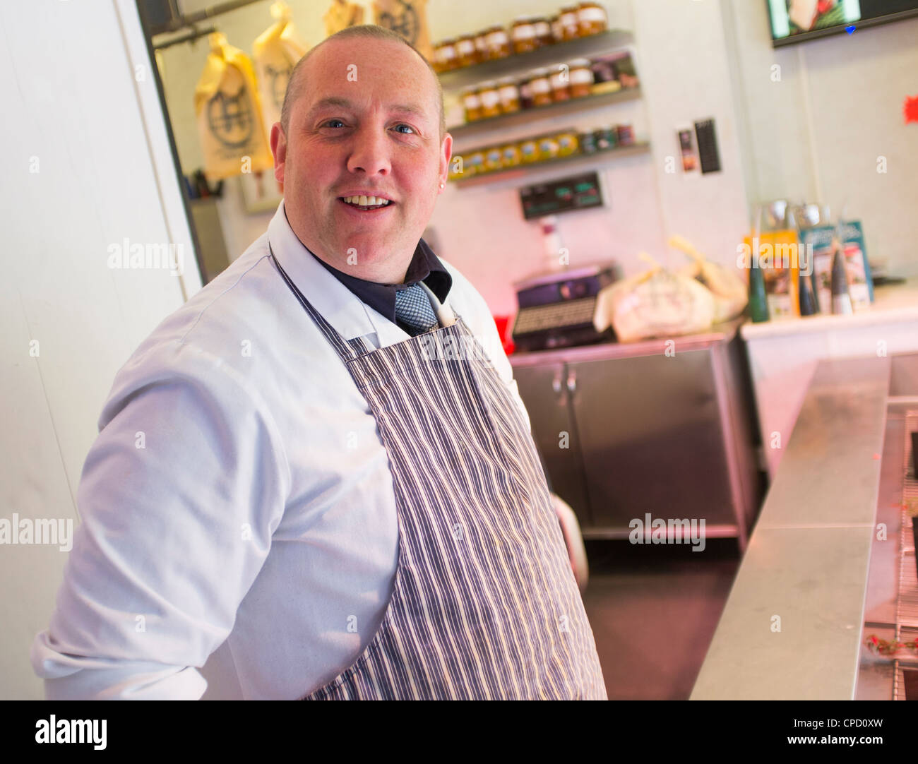 Portrait of a smiling independent small trader in his local butchers ...