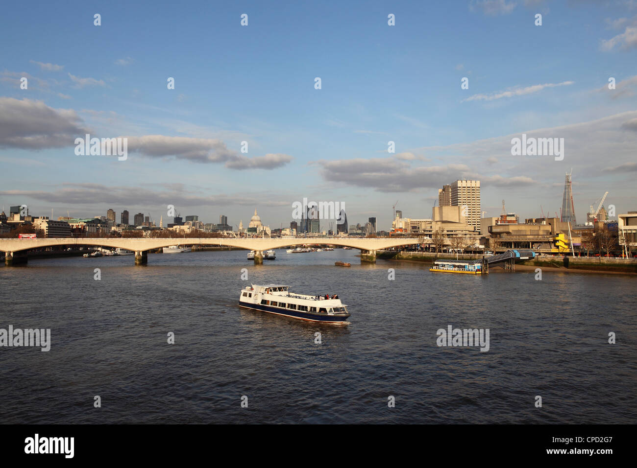A cruise boat on River Thames, ahead of Waterloo Bridge and the skyline ...
