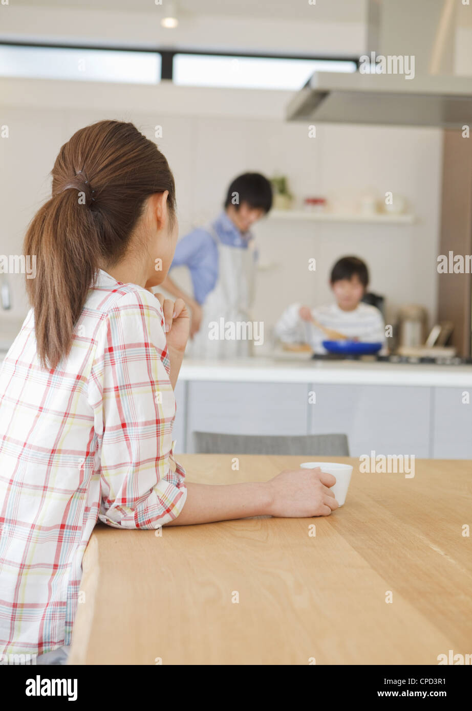 Mother watching father and son cooking Stock Photo - Alamy