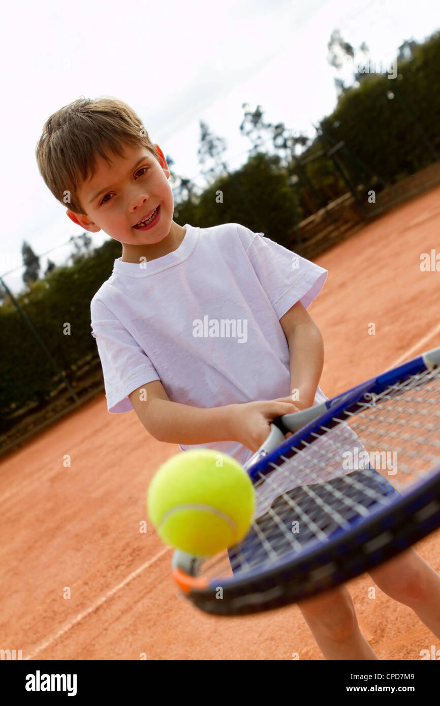 Hispanic boy balancing tennis ball on racquet Stock Photo - Alamy