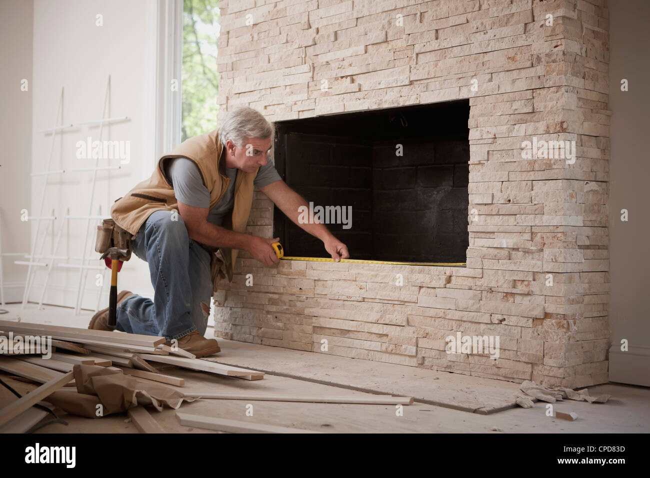 Caucasian carpenter measuring fireplace Stock Photo - Alamy