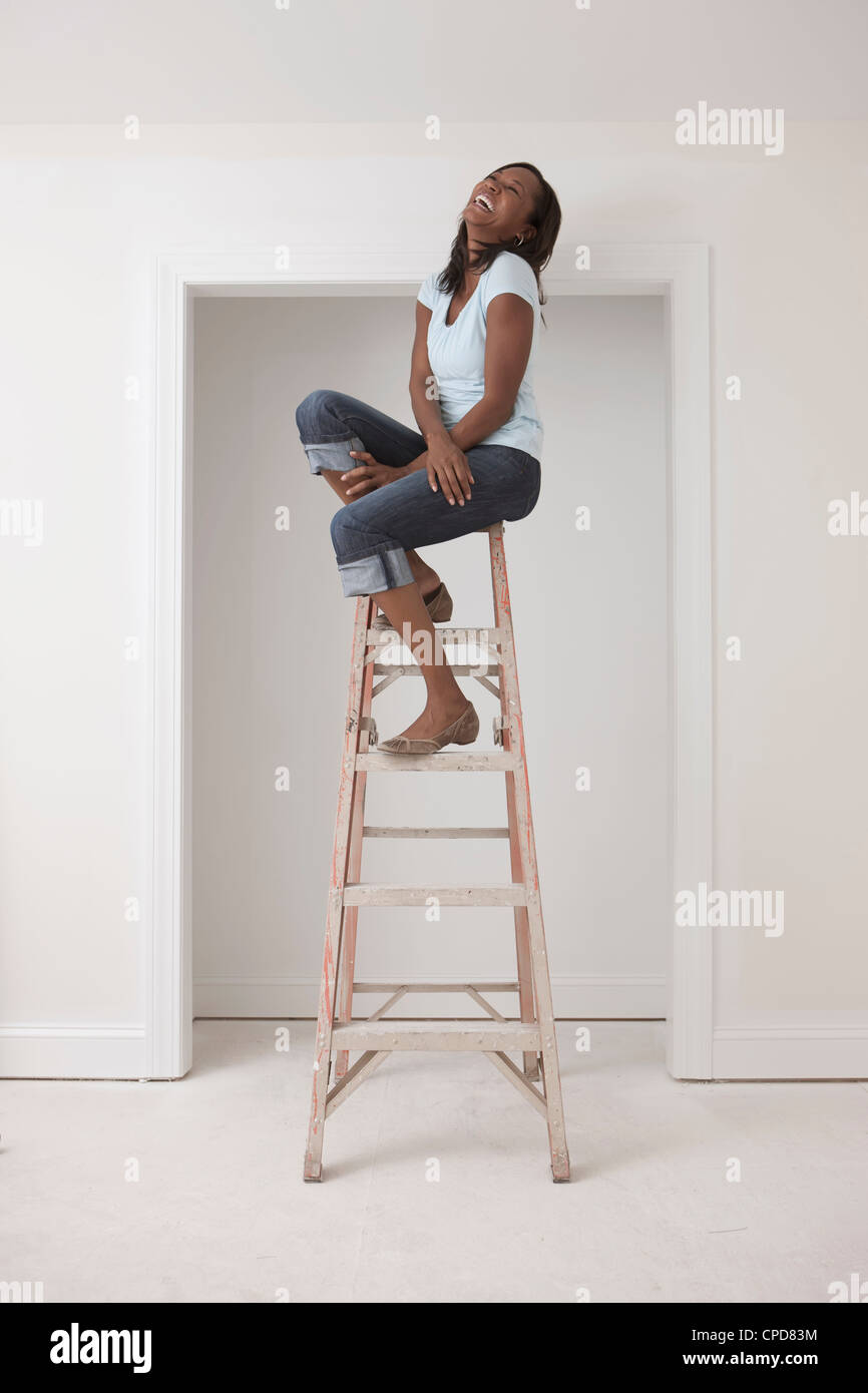 Black woman sitting on top of ladder Stock Photo - Alamy