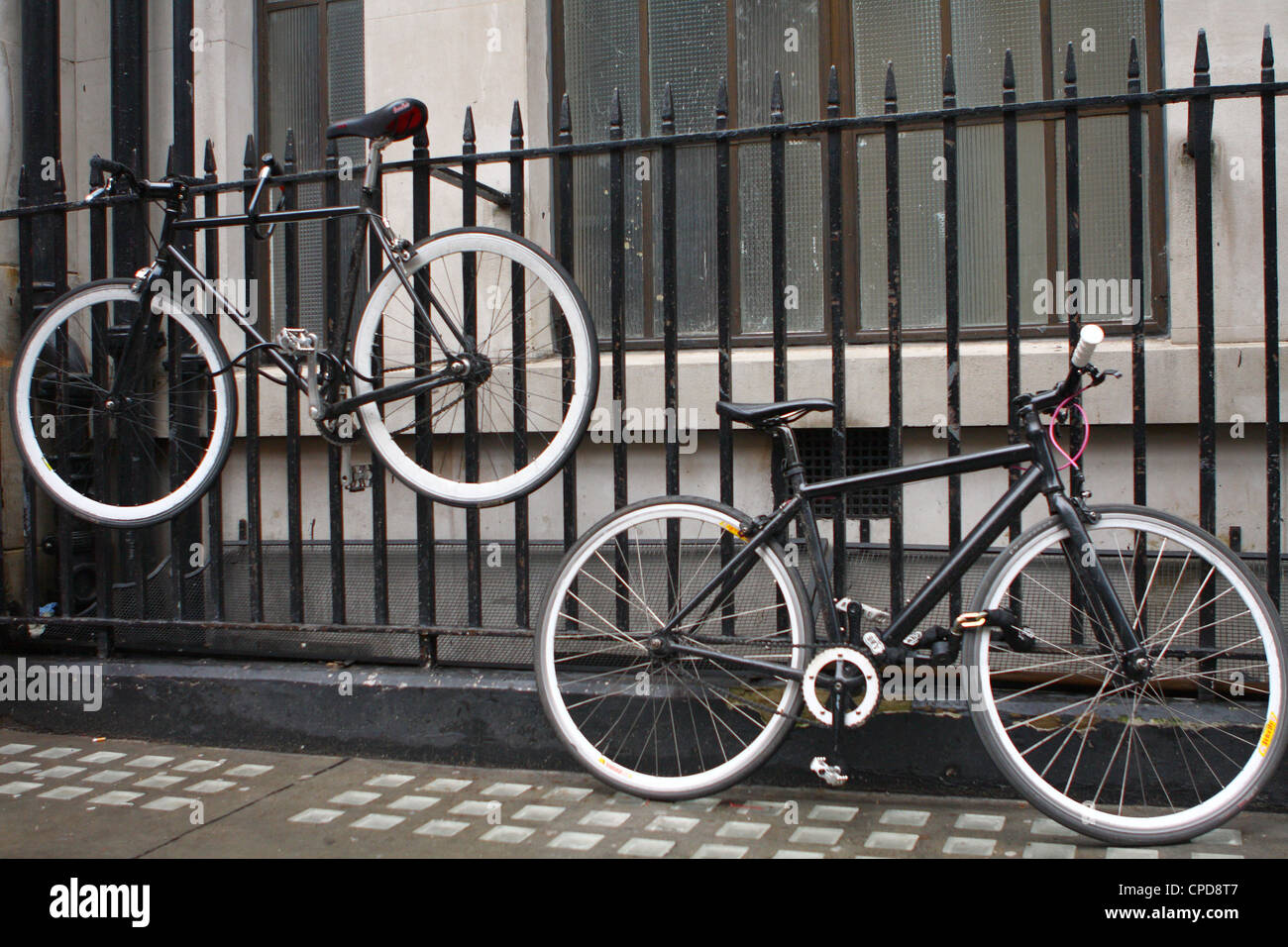 Two bicycles chained to railings in London Stock Photo - Alamy