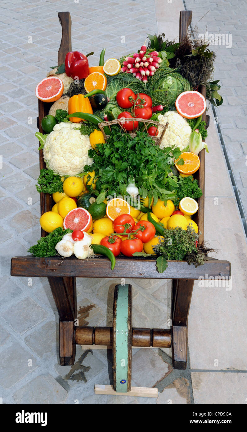 A wheel barrow used to display fruit and vegetables outside of a shop ...