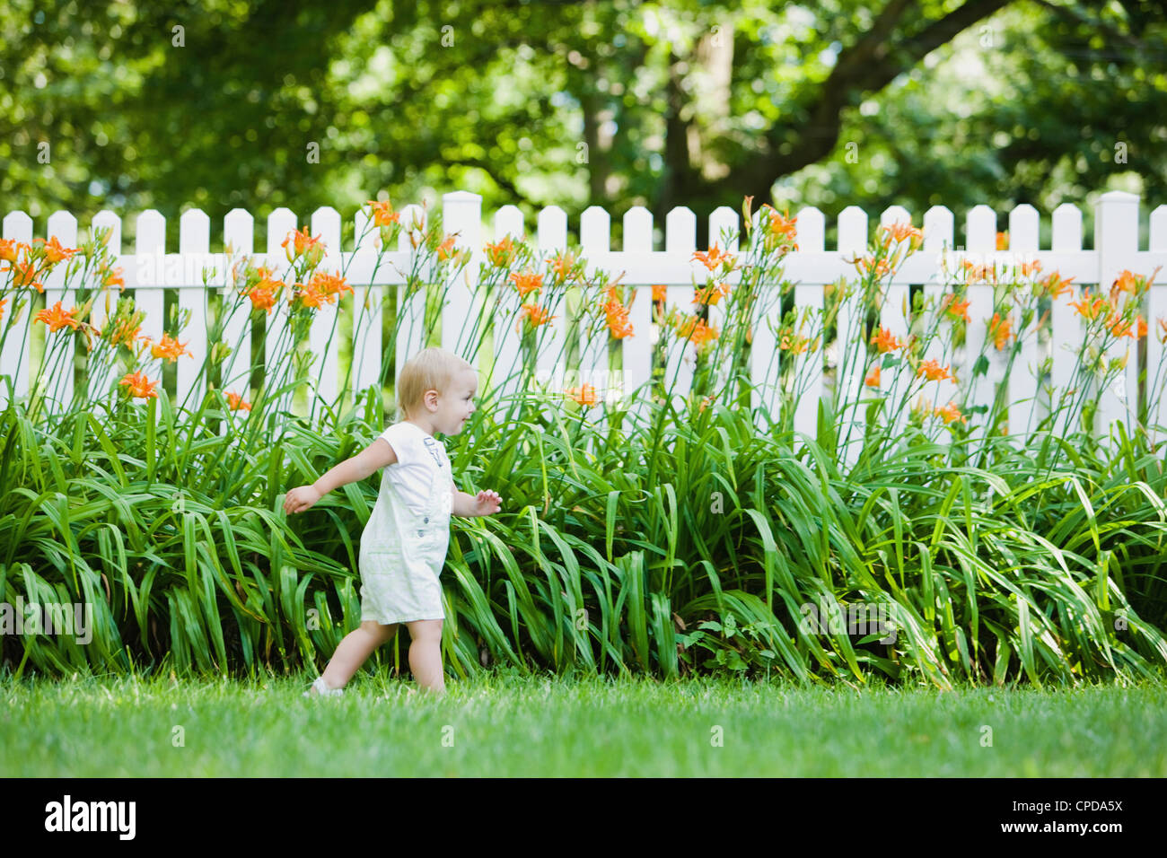 Caucasian girl exploring flowers in backyard Stock Photo - Alamy