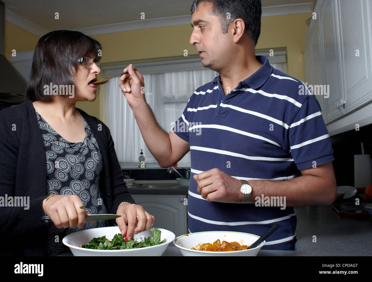 An Asian woman being spoon fed by her husband Stock Photo - Alamy