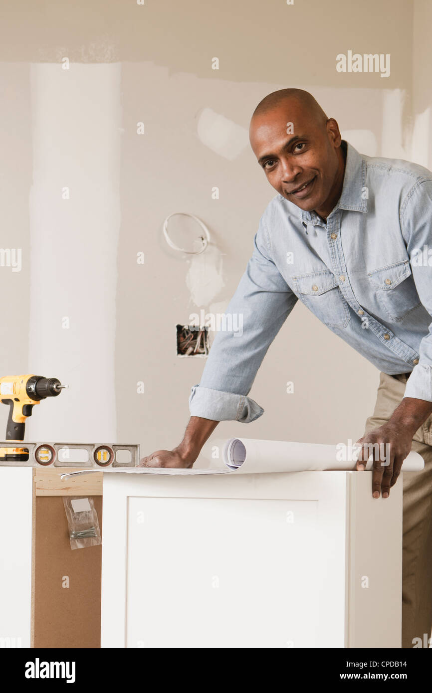 African American man looking at blueprints in unfinished room Stock ...