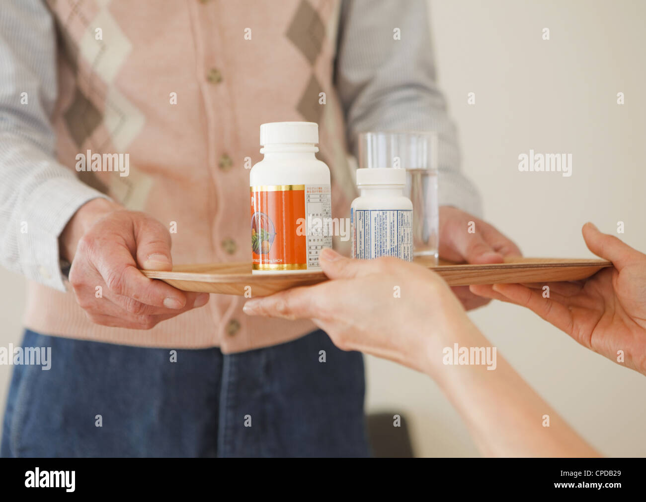 Senior couple handing over a tray of supplements Stock Photo - Alamy