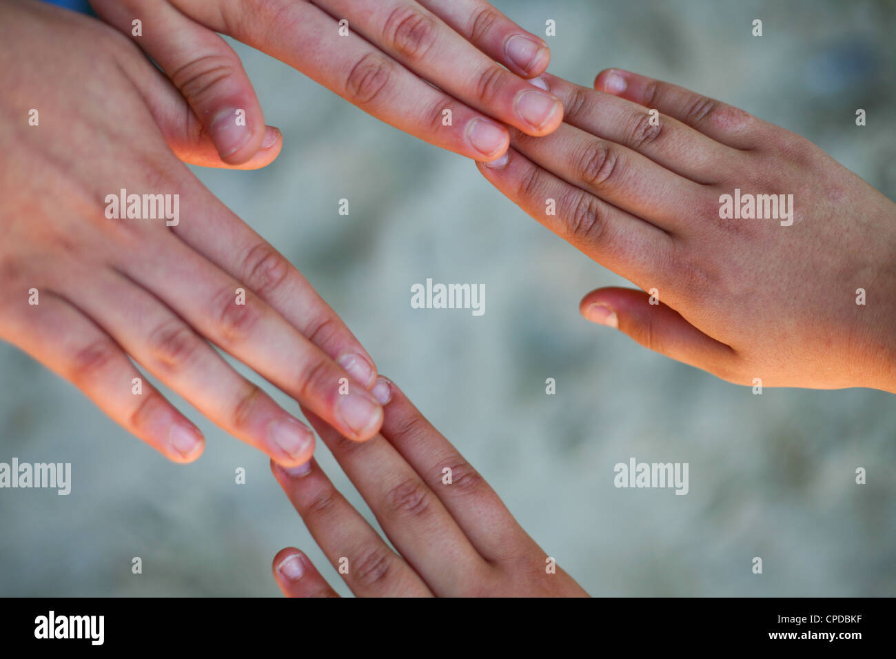 Two pairs of ethnic children's hands touching over a neutral background ...