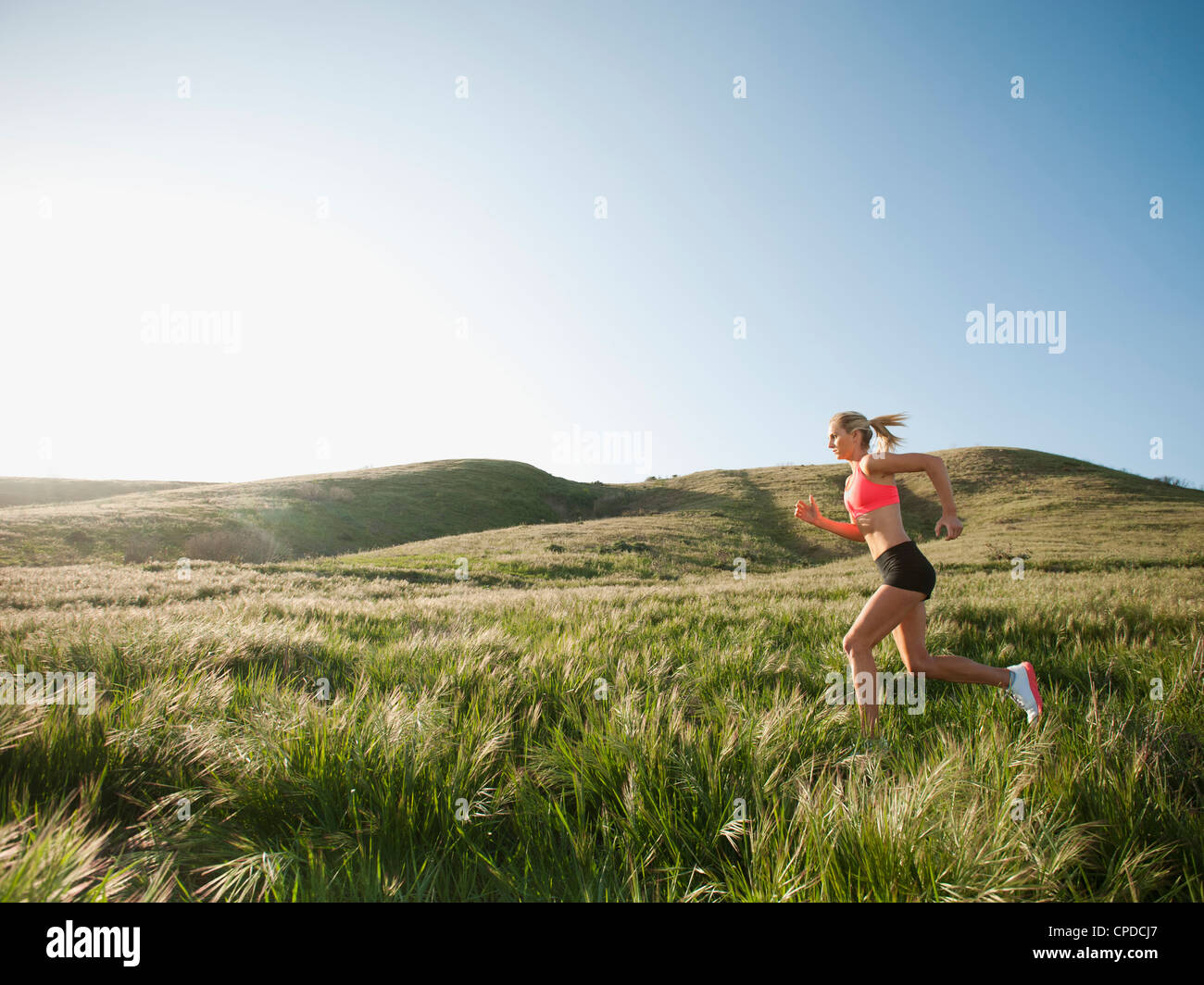 Caucasian woman running in remote field Stock Photo - Alamy