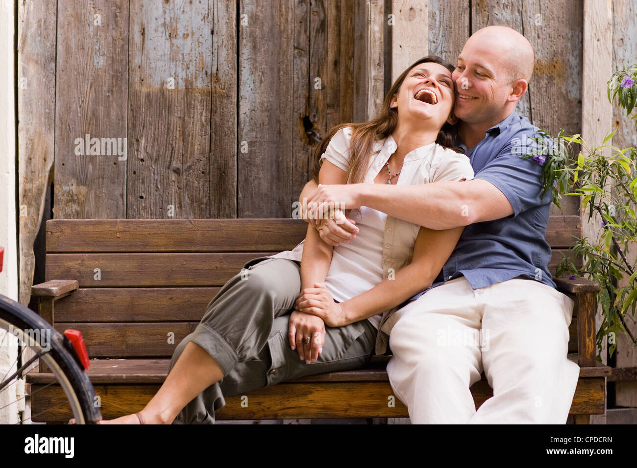 Laughing couple hugging on bench Stock Photo - Alamy