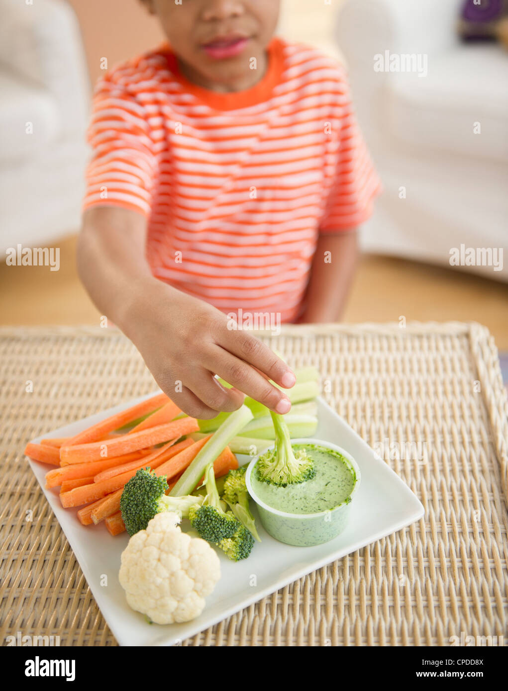 Black boy eating vegetables and dip Stock Photo - Alamy