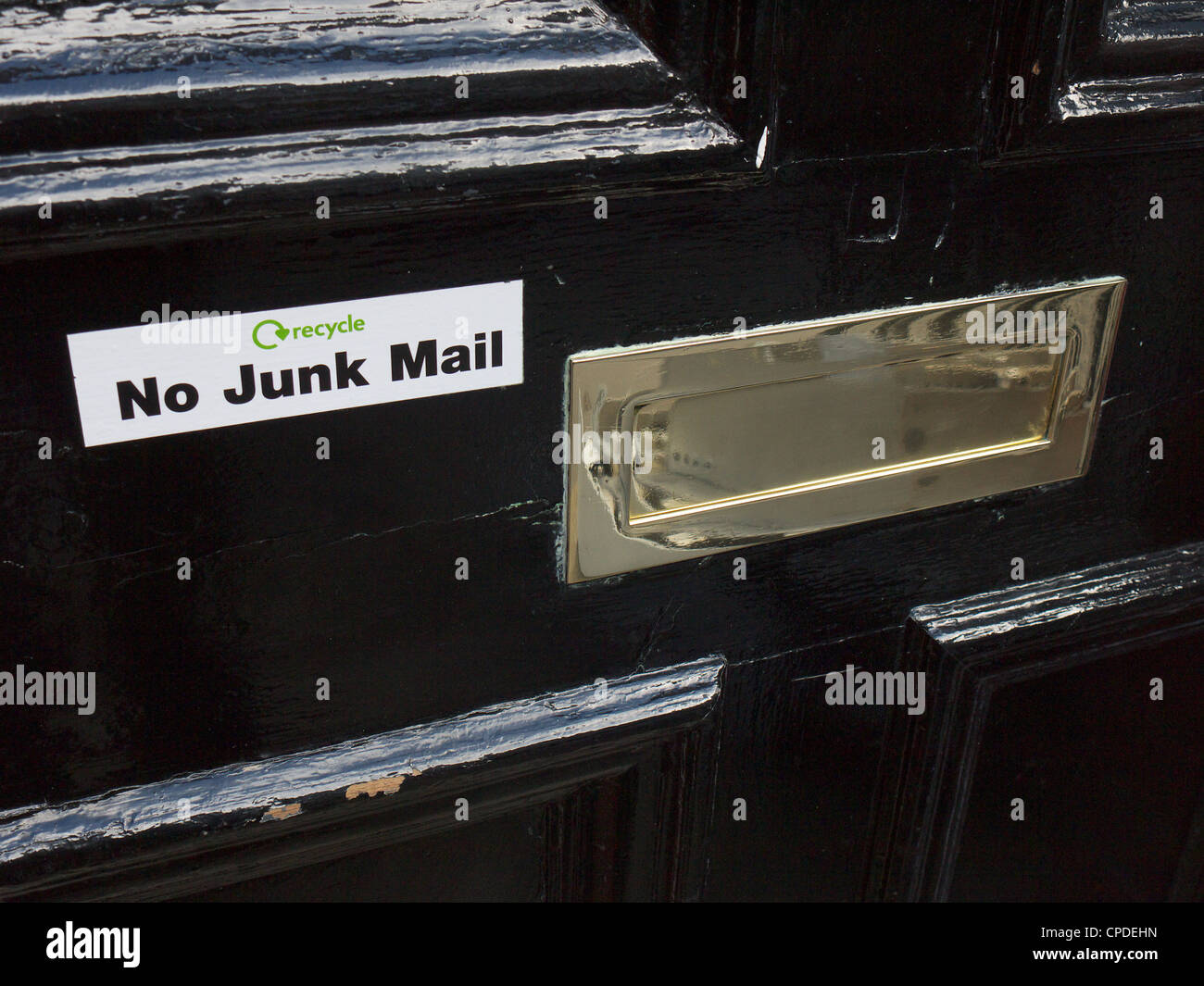 brass letter box on a black door with a no junk mail sticker on the ...