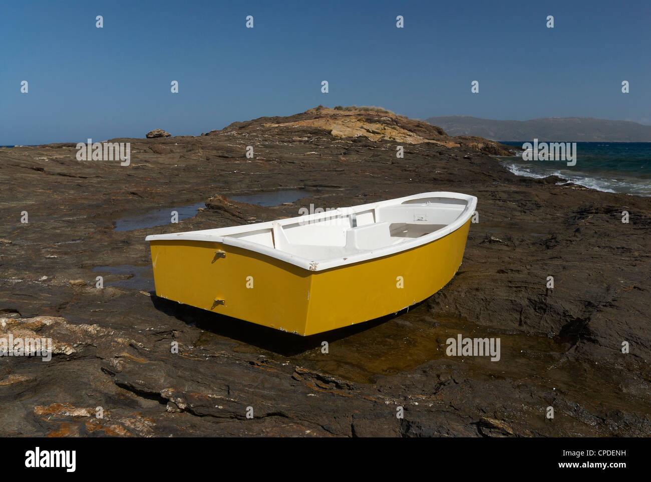 A yellow boat standing on rock formations at Keratea near Lavrio Stock ...