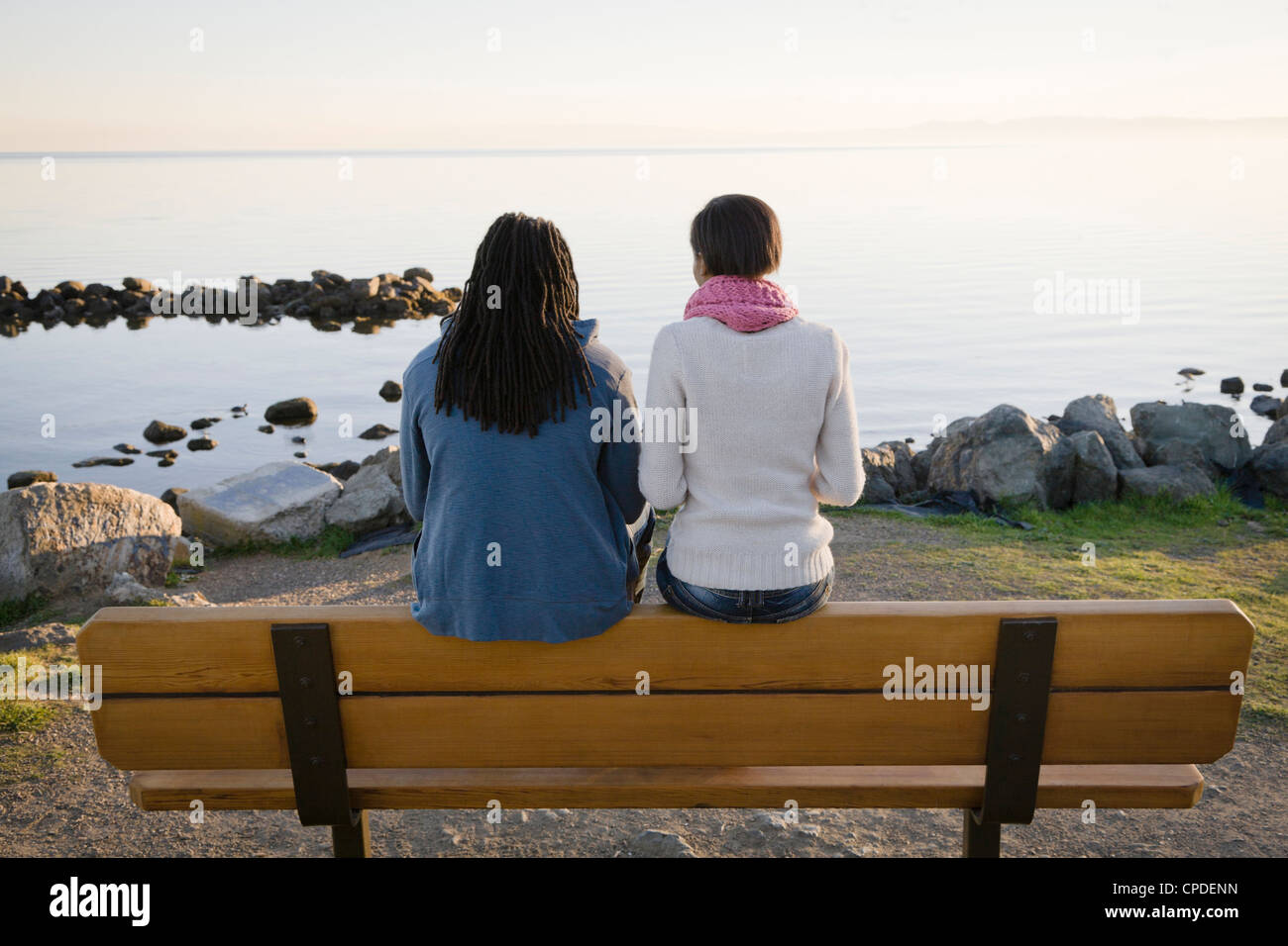 Black couple sitting on bench near shore Stock Photo - Alamy