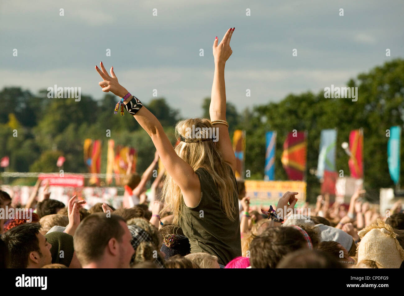 Girl at a music festival on shoulders in the crowd cheering Stock Photo ...