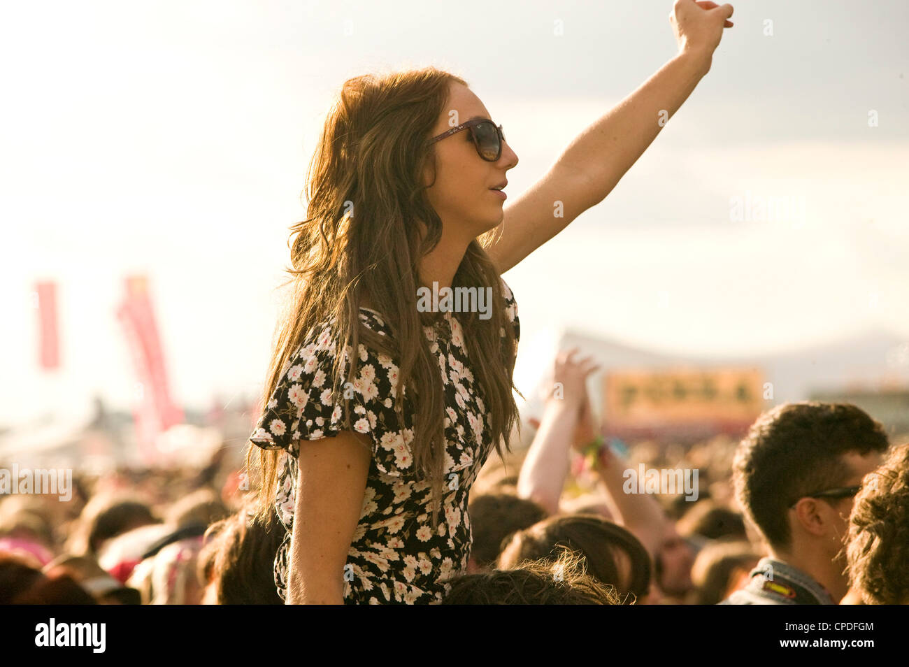 Girl at a music festival on shoulders in the crowd cheering Stock Photo ...