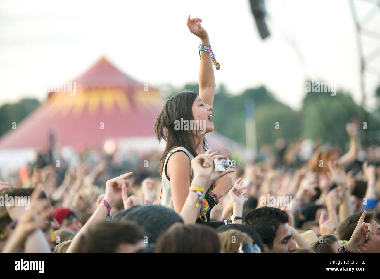 Girl at a music festival on shoulders in the crowd cheering Stock Photo ...