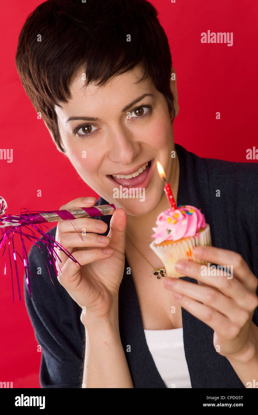 A woman smiles before blowing out her candle and eating her cupcake ...