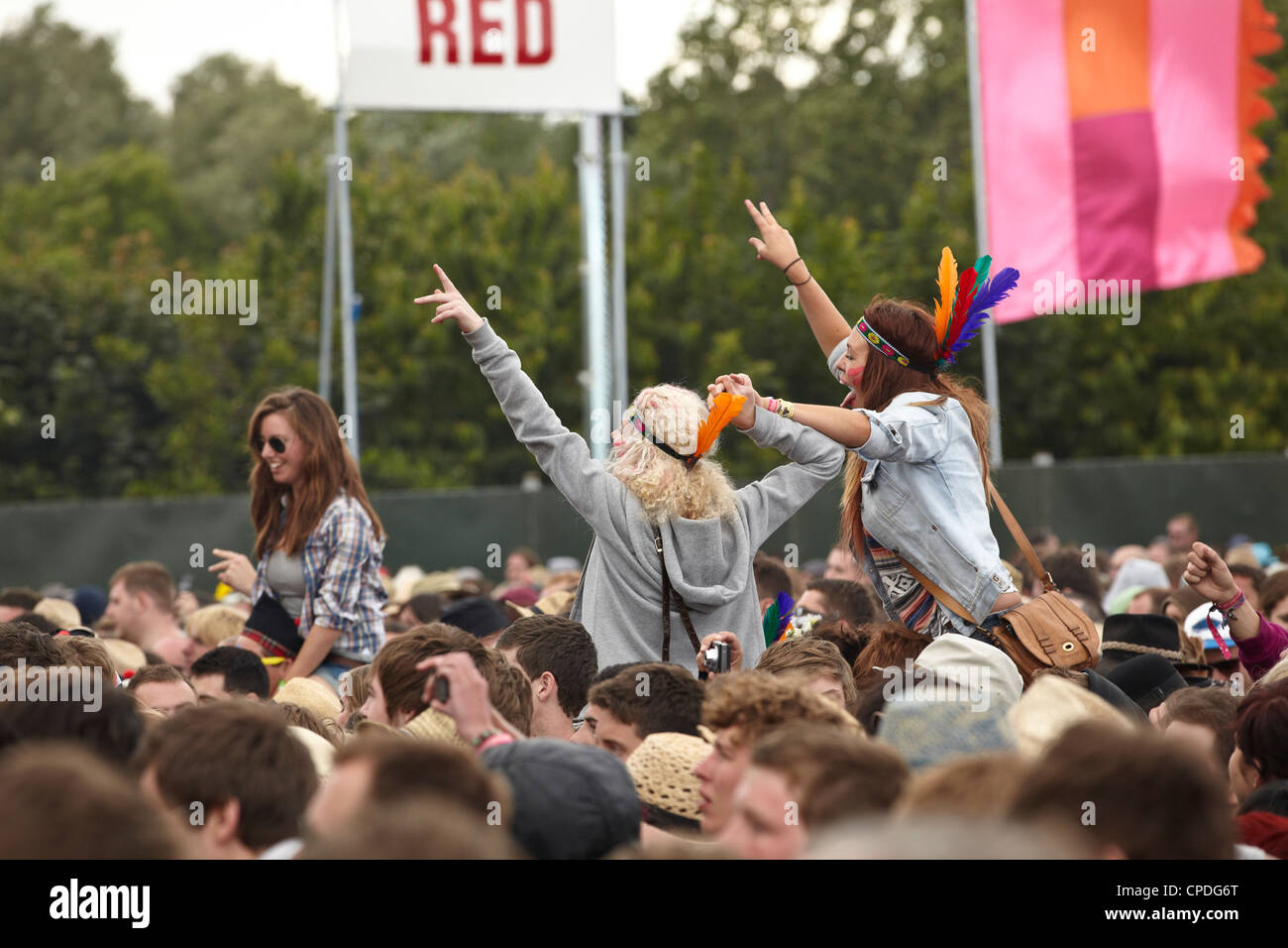 Girl on shoulders cheering in the crowd at gig at a music festival ...
