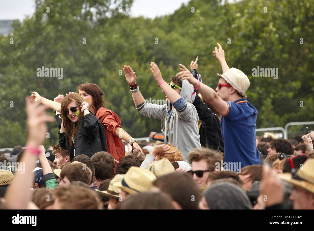 Girl on shoulders cheering in the crowd at gig at a music festival ...