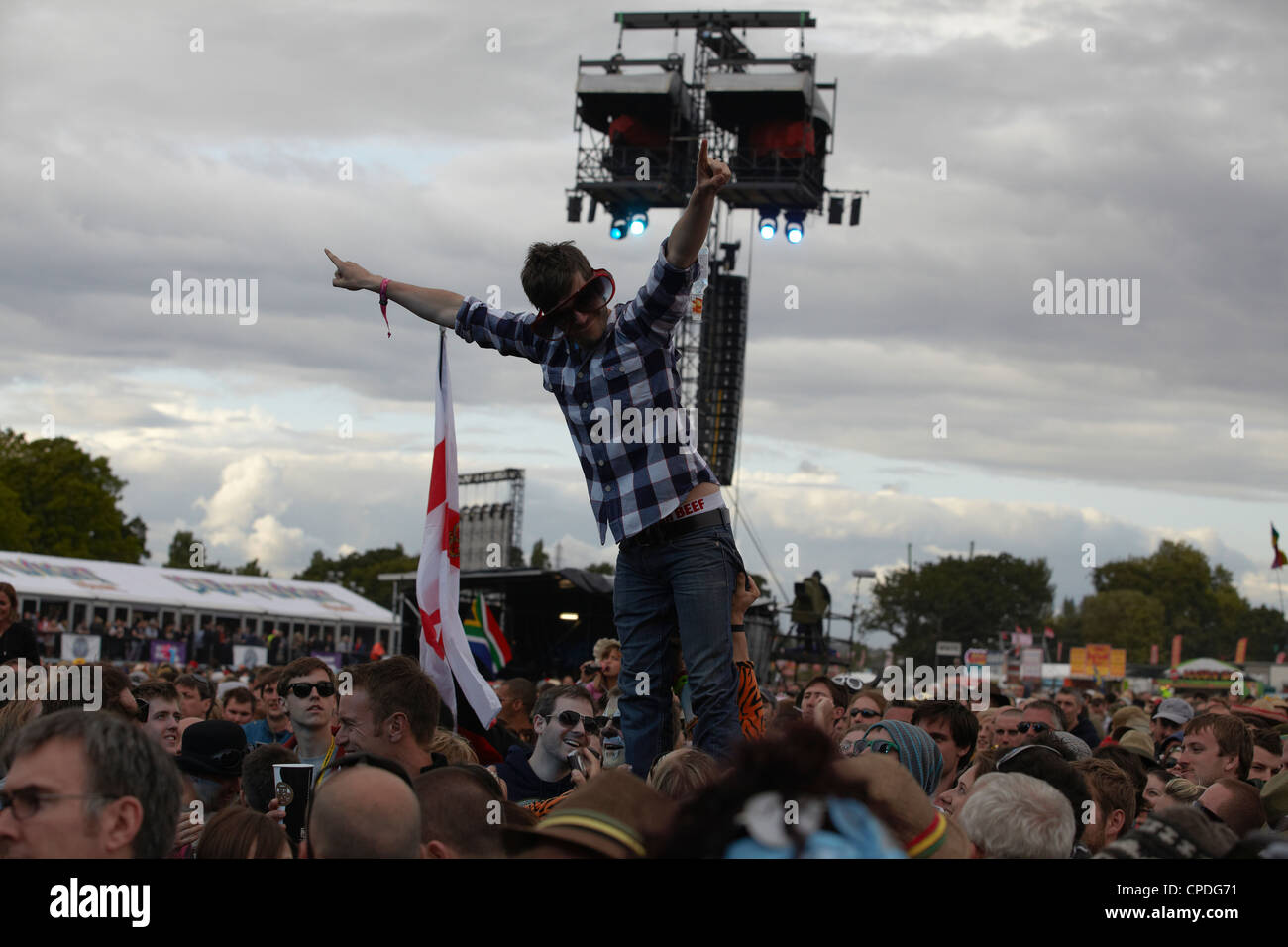 Boy standing on shoulders cheering in the crowd at gig at a music ...
