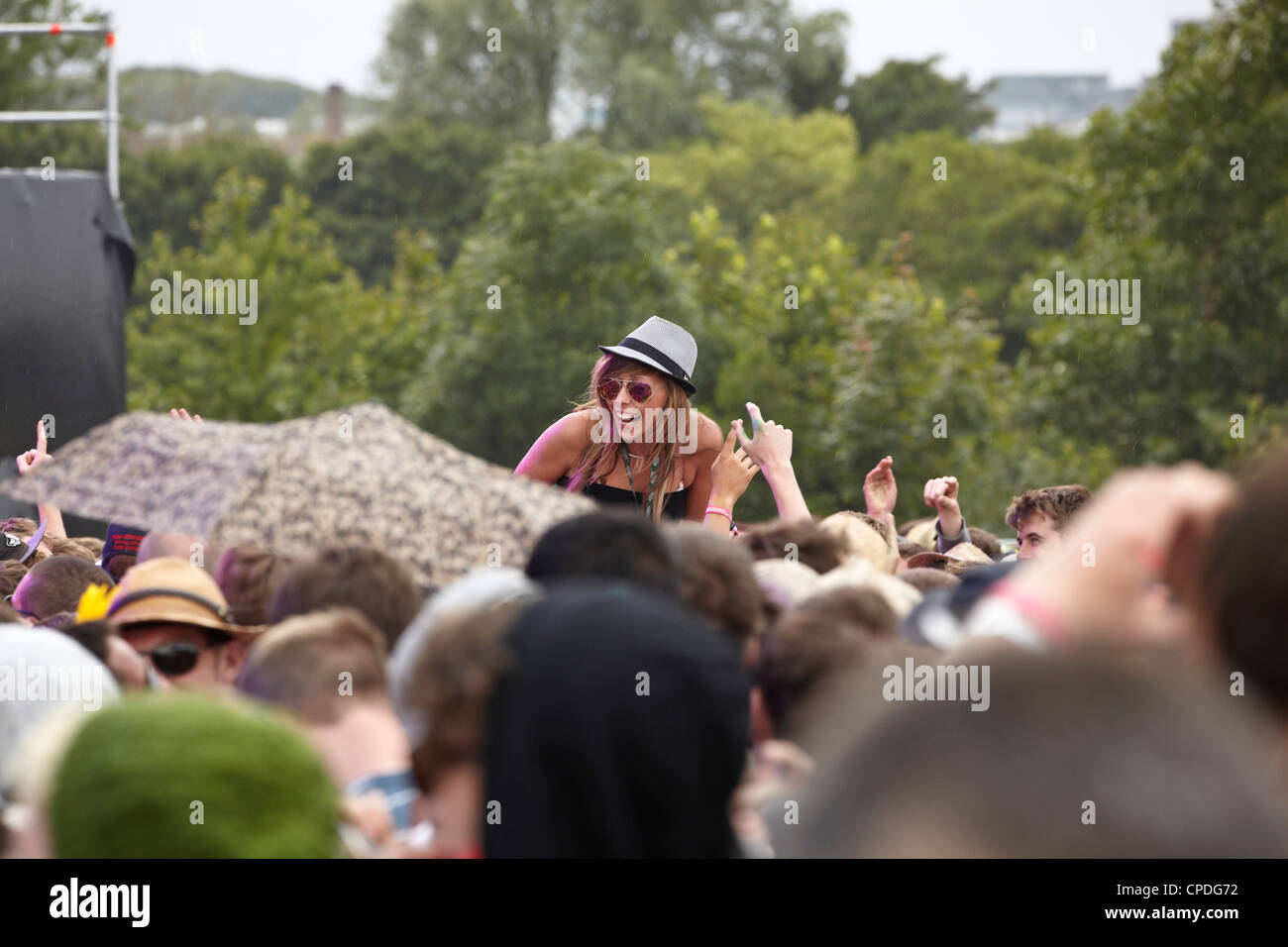 Girl on shoulders cheering in the crowd at gig at a music festival ...
