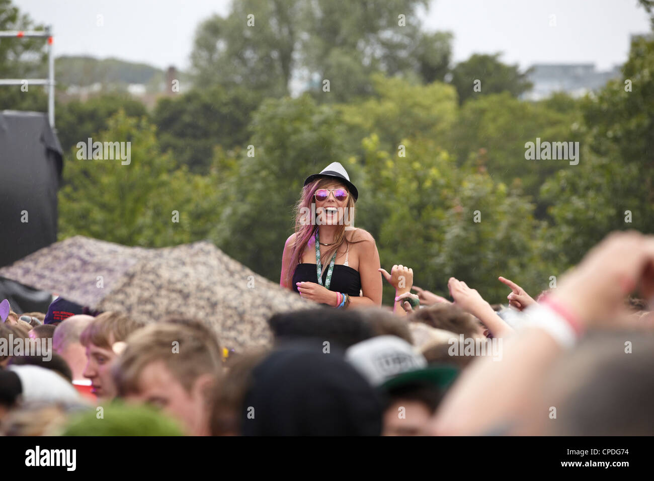 Girl on shoulders cheering in the crowd at gig at a music festival ...