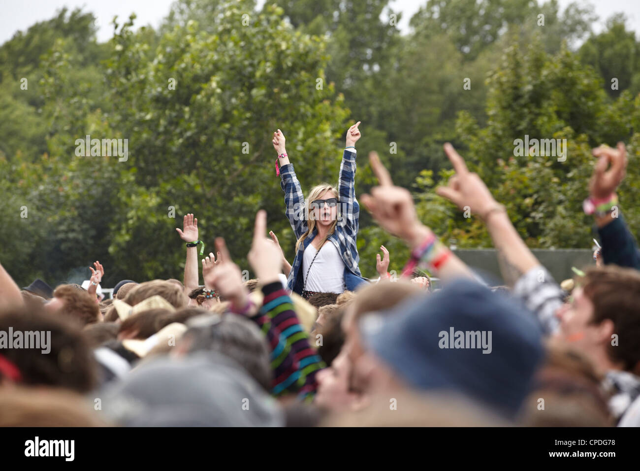 Girl on shoulders cheering in the crowd at gig at a music festival ...