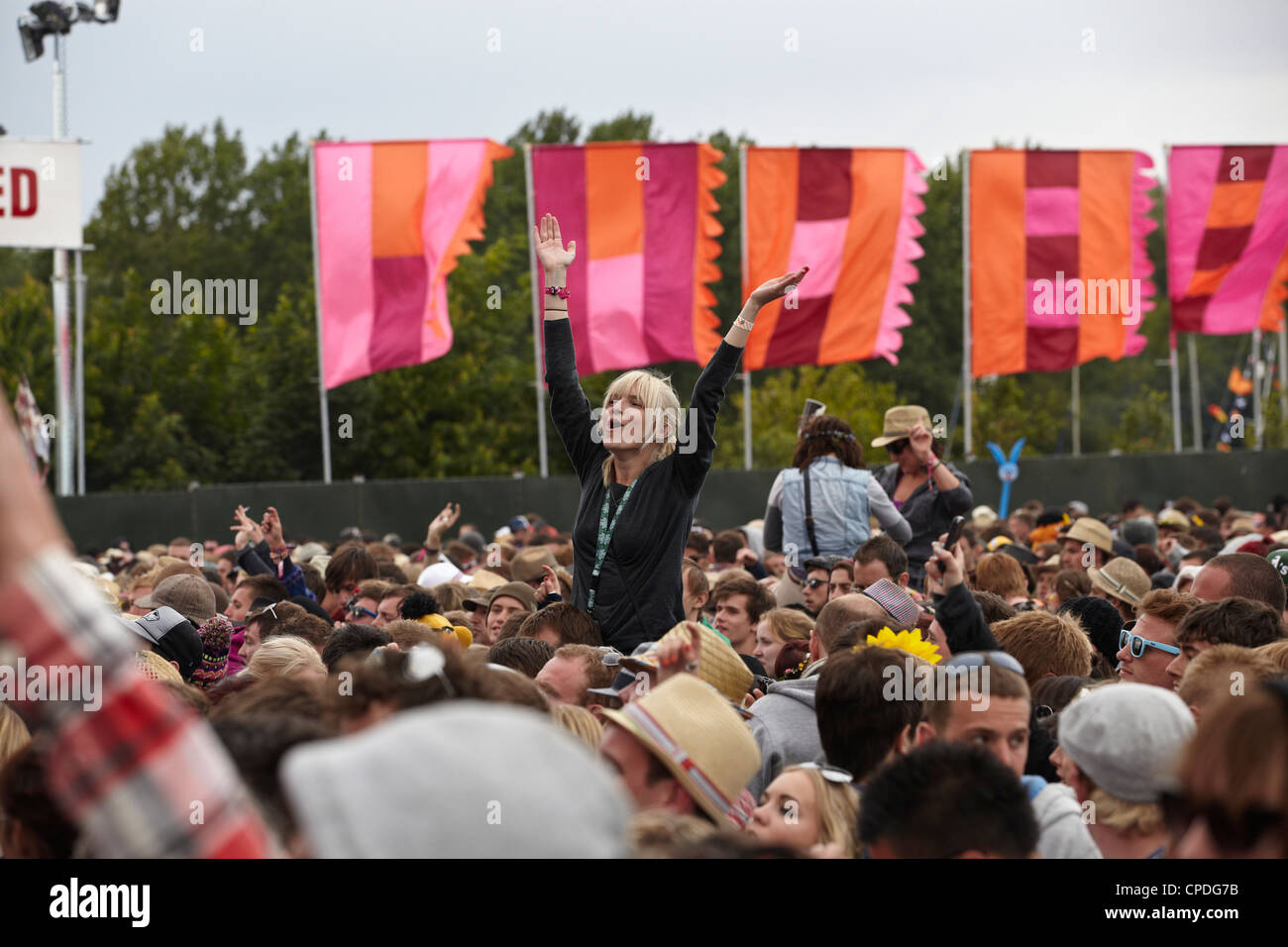 Girl on shoulders cheering in the crowd at gig at a music festival ...