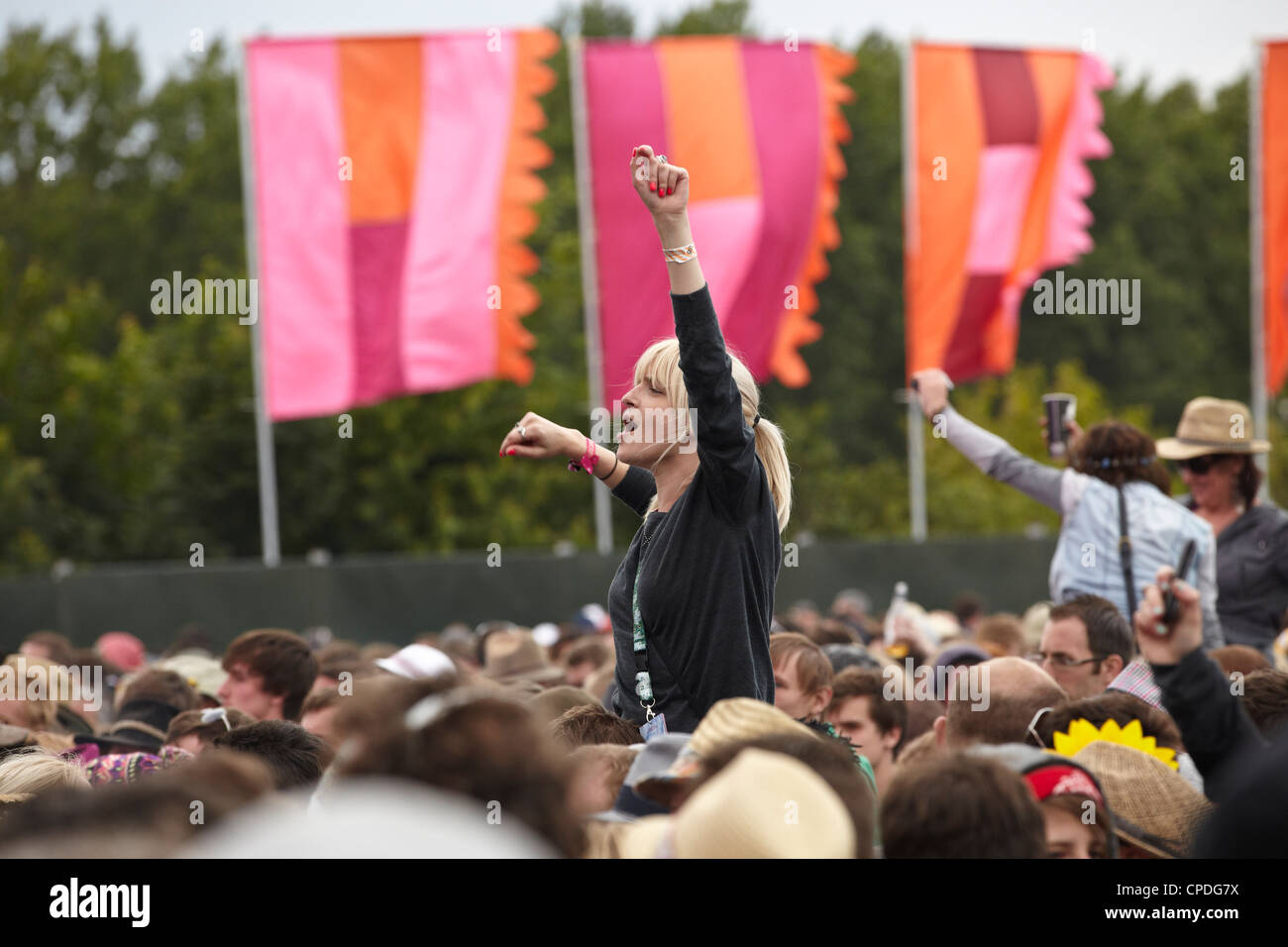 Girl on shoulders cheering in the crowd at gig at a music festival ...