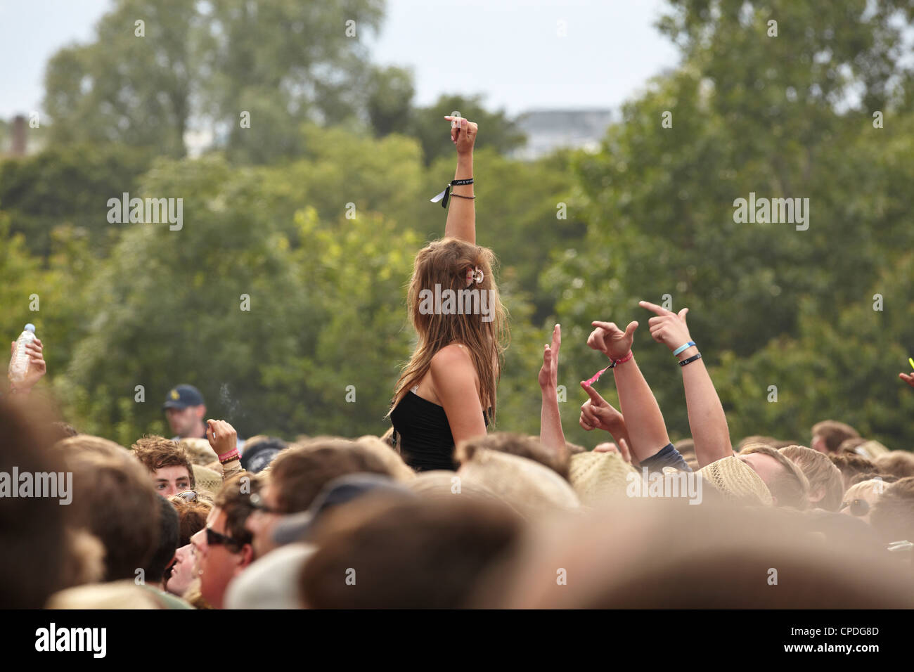 Girl on shoulders cheering in the crowd at gig at a music festival ...