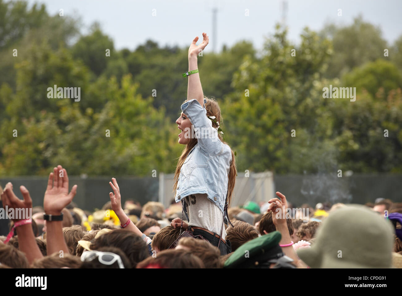 Girl on shoulders cheering in the crowd at gig at a music festival ...