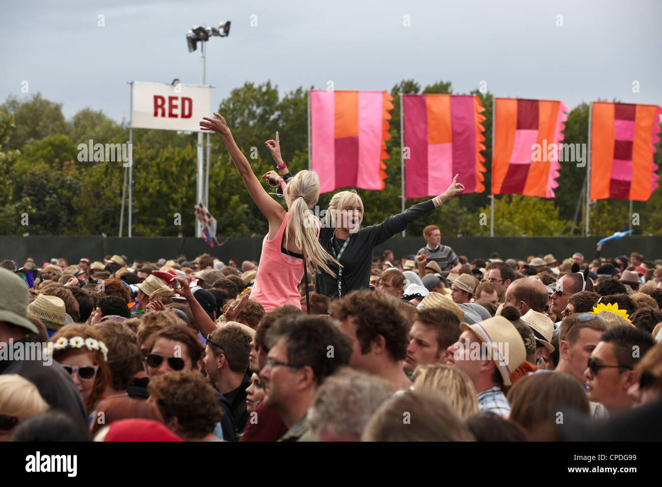 Girl on shoulders cheering in the crowd at gig at a music festival ...