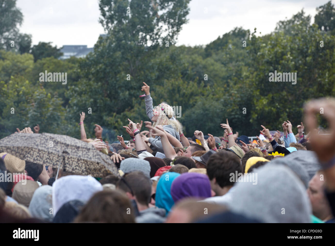 Girl on shoulders cheering in the crowd at gig at a music festival ...