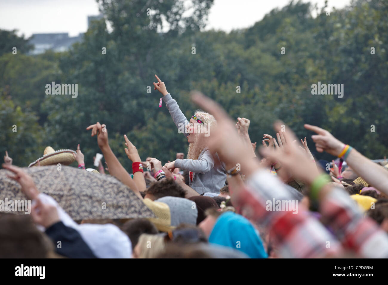 Girl on shoulders cheering in the crowd at gig at a music festival ...
