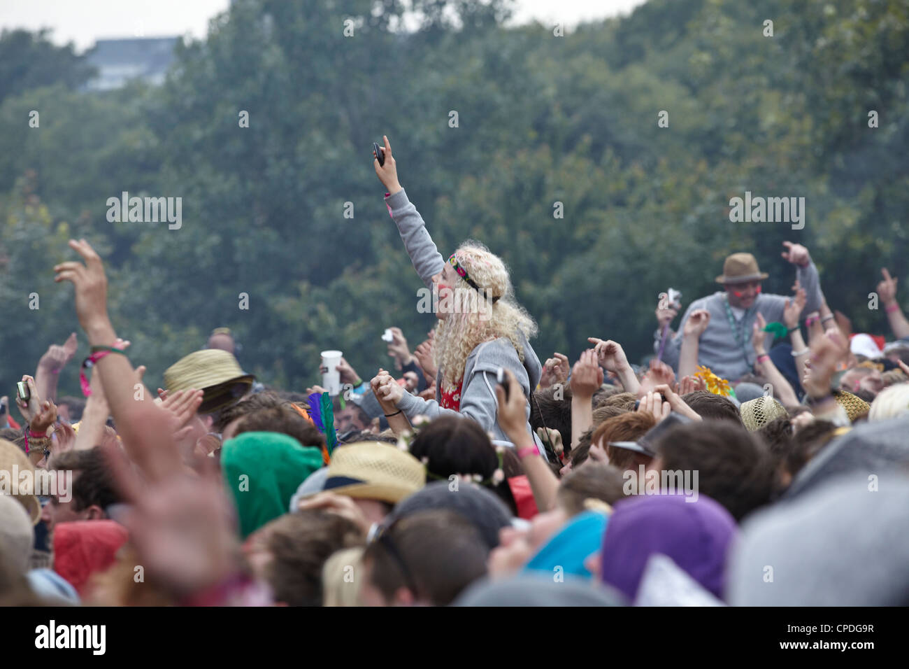 Girl on shoulders cheering in the crowd at gig at a music festival ...