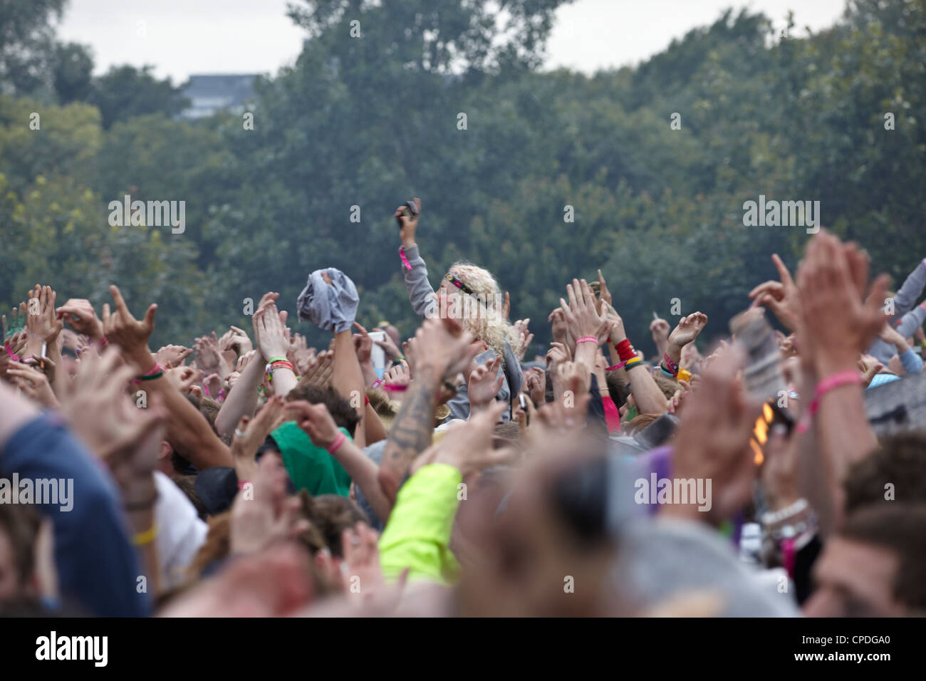 Girl on shoulders cheering in the crowd at gig at a music festival ...