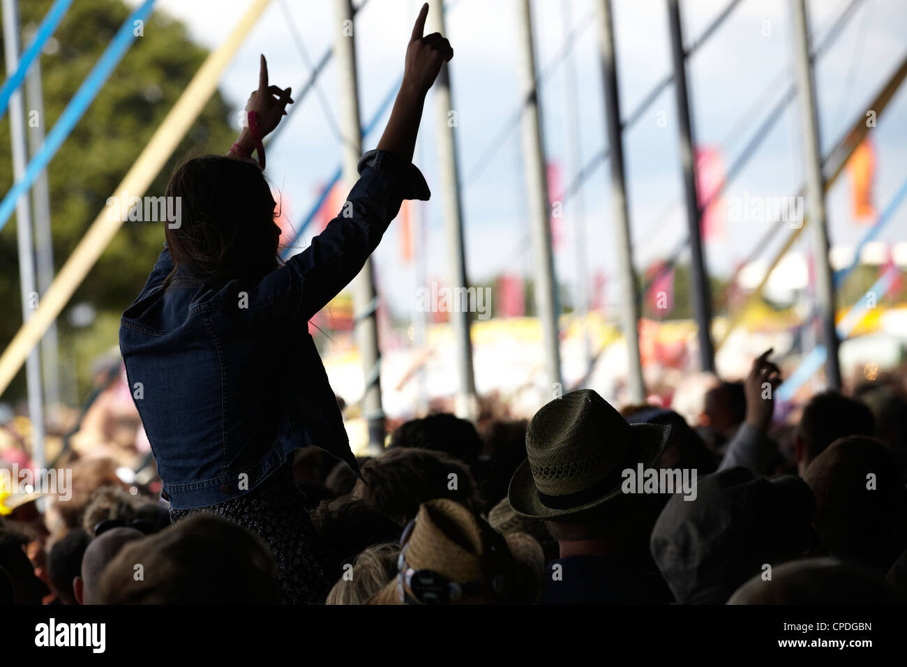 Girl on shoulders cheering in the crowd at gig at a music festival ...
