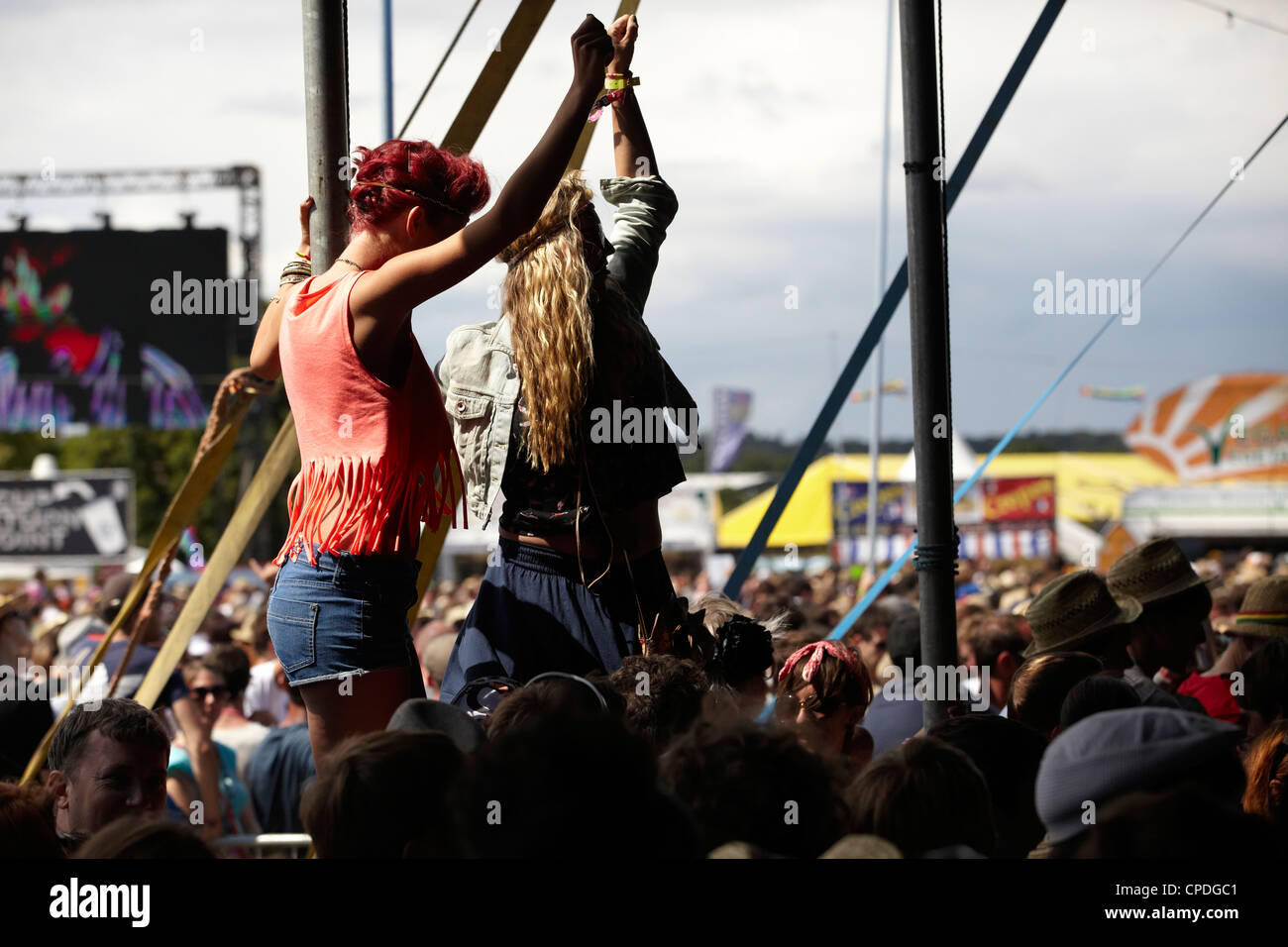 Girl on shoulders cheering in the crowd at gig at a music festival ...